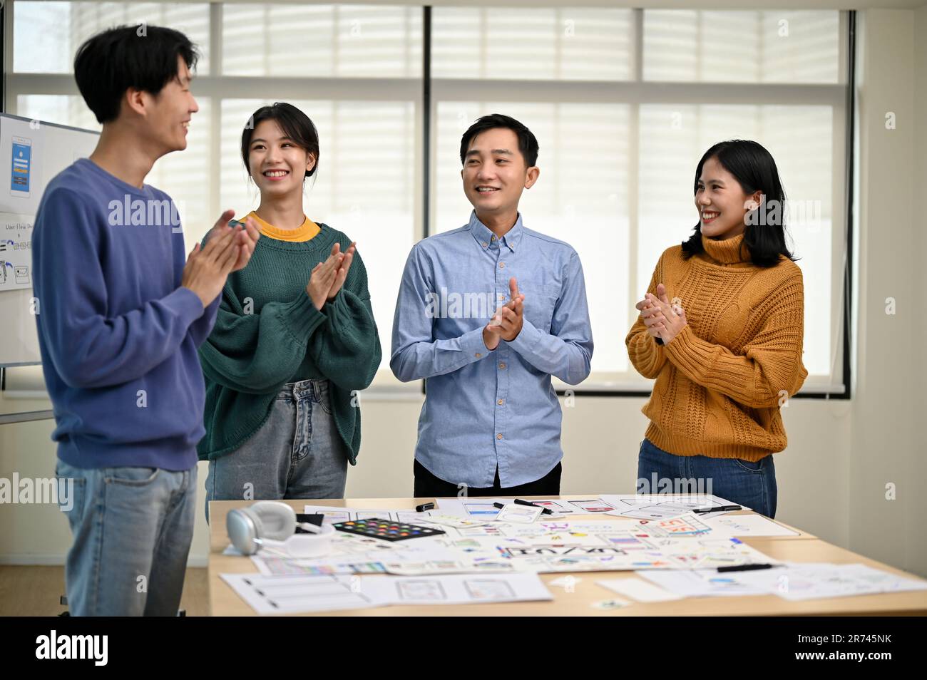 A group of cheerful Asian graphic designers or developers is standing ...