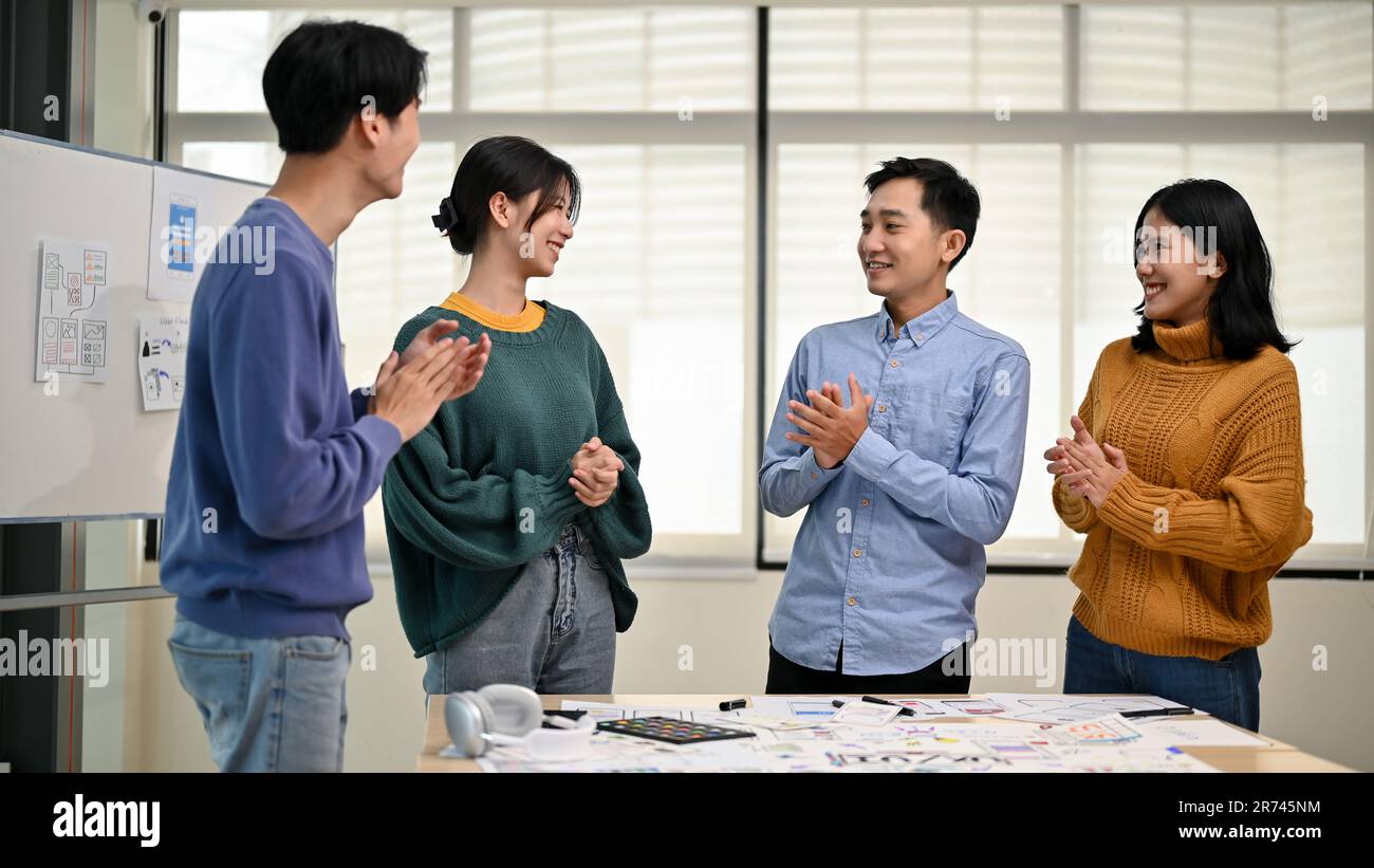 A group of cheerful Asian graphic designers or developers is standing ...