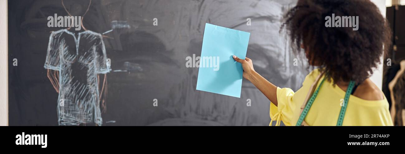 African-American teacher shows blank blue paper against blackboa Stock ...