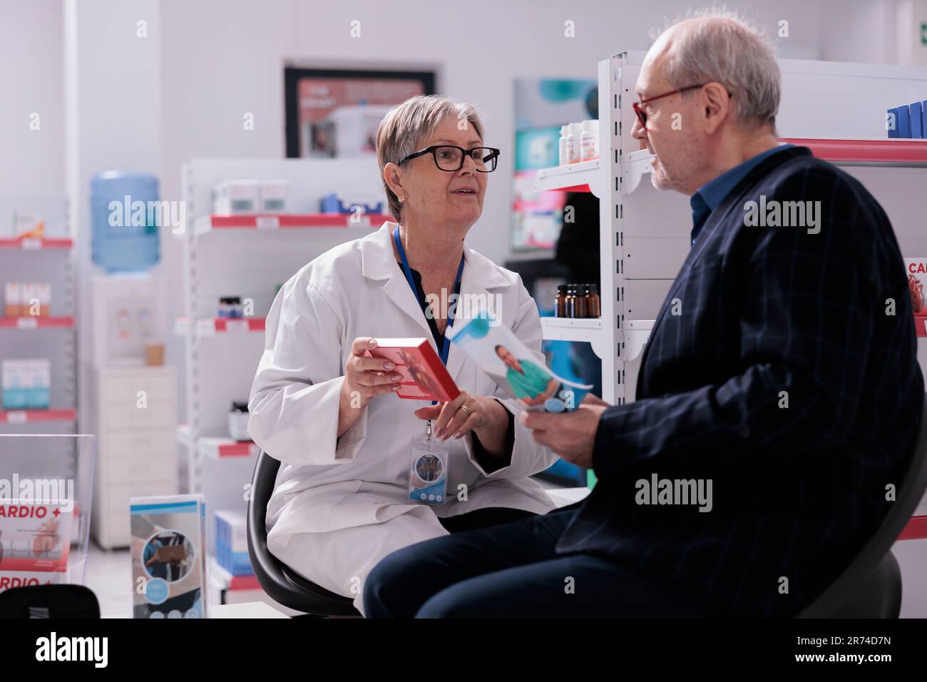 Pharmacy chemist advising elderly man heart multivitamin package ...