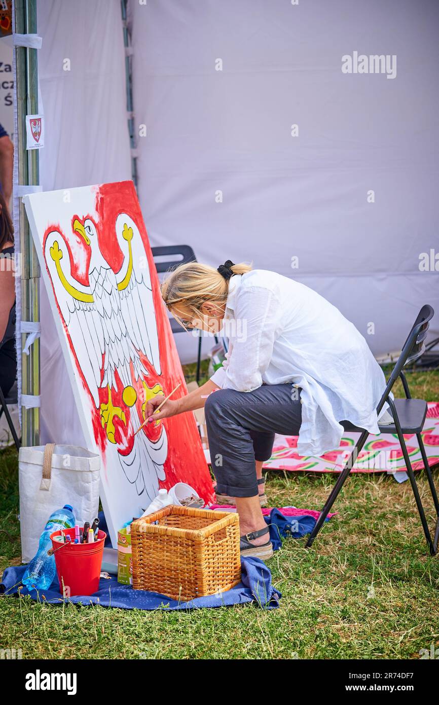 A young female artist painting the Polish coat of arms on canvas in a ...