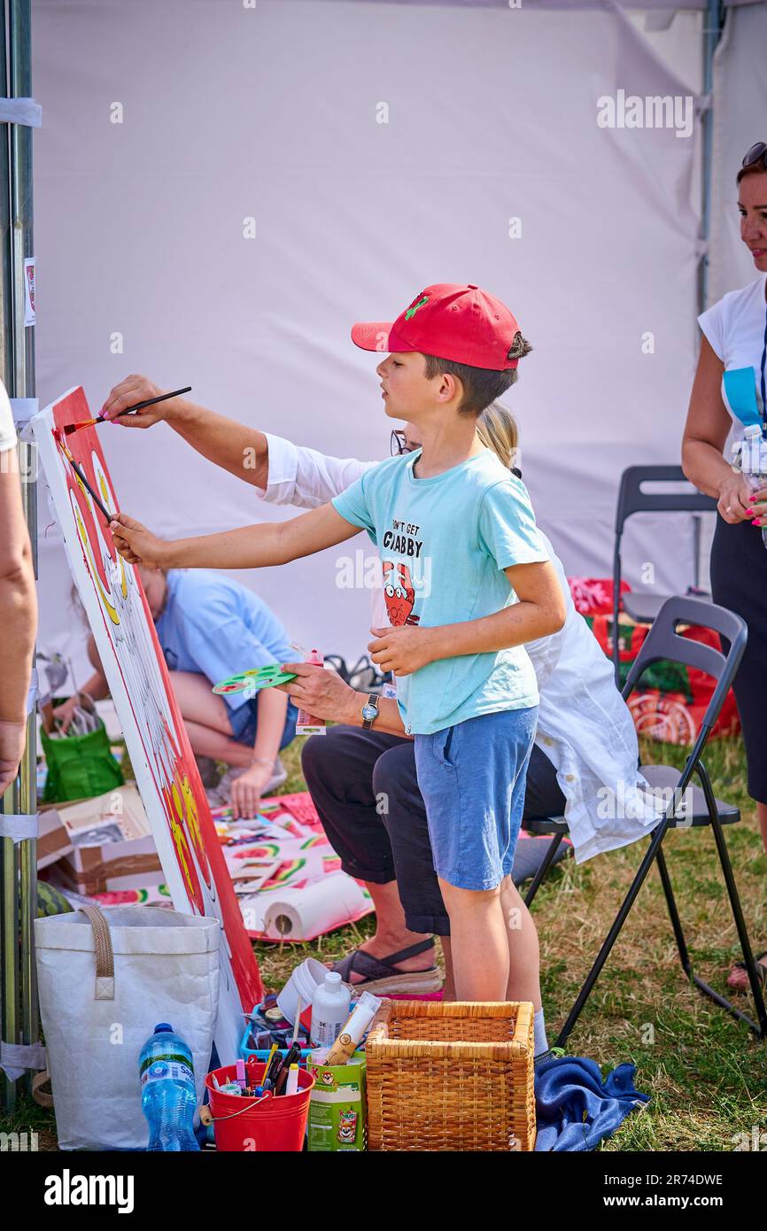 A young boy artist painting the Polish coat of arms on canvas in a lush ...