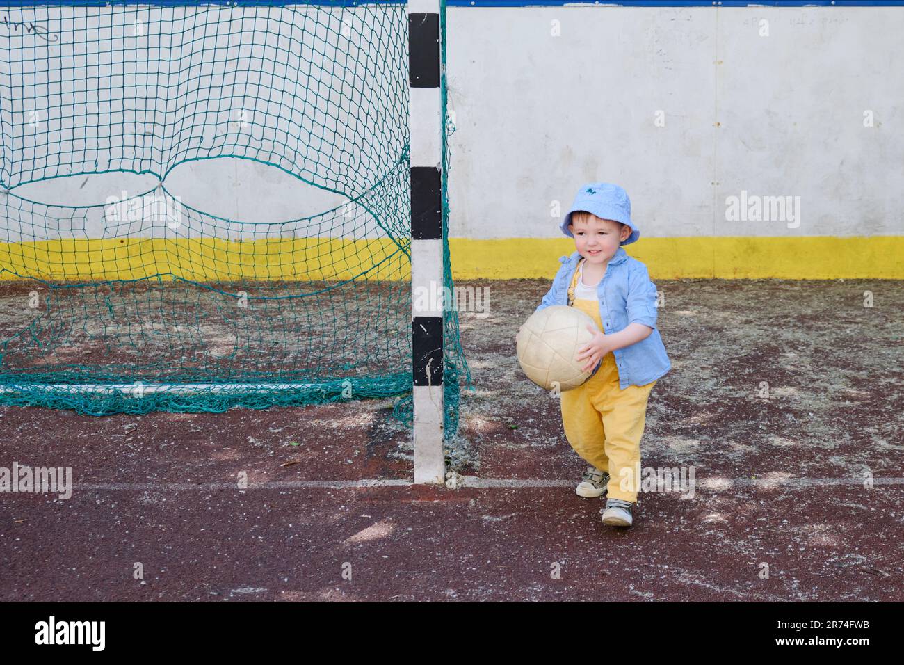 The child's happiness is evident as they run after the ball on the ...