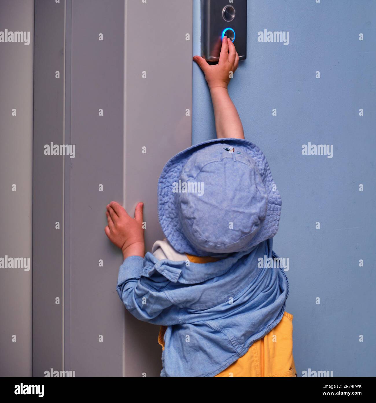 Toddler baby calls the elevator by pressing the button in the entrance ...