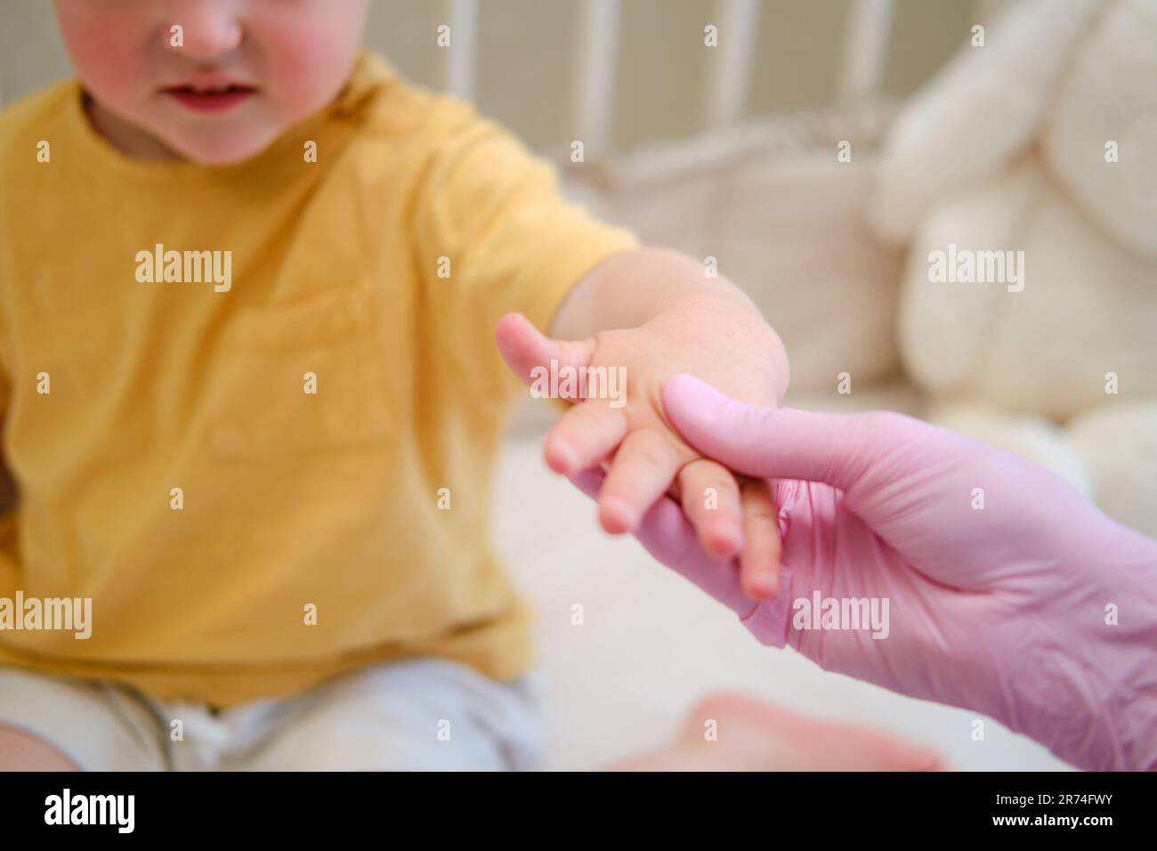 Doctor does gymnastics and hands massage to a toddler baby. Nurse in ...