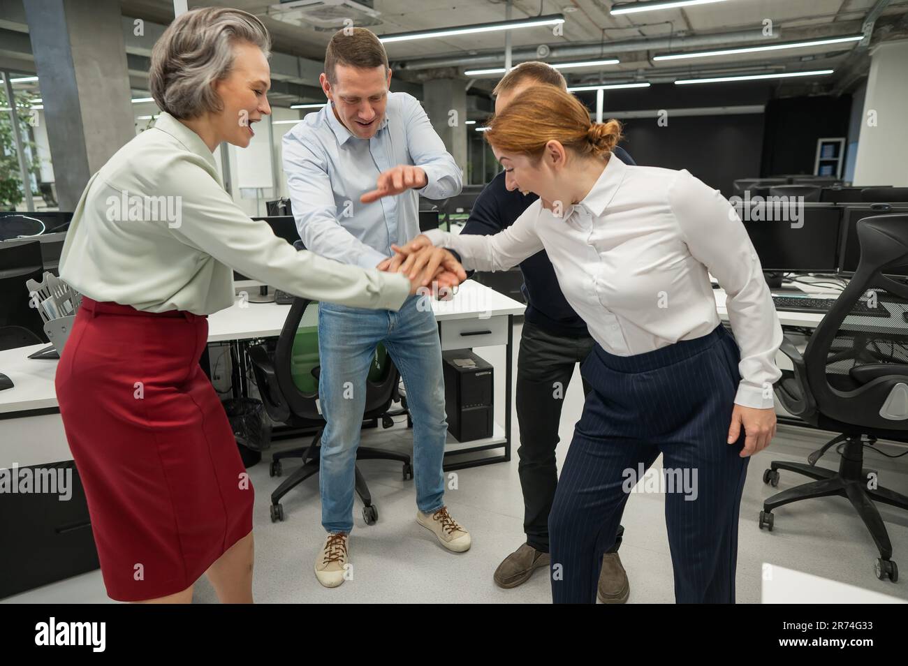 Four colleagues give the low five in the office Stock Photo - Alamy