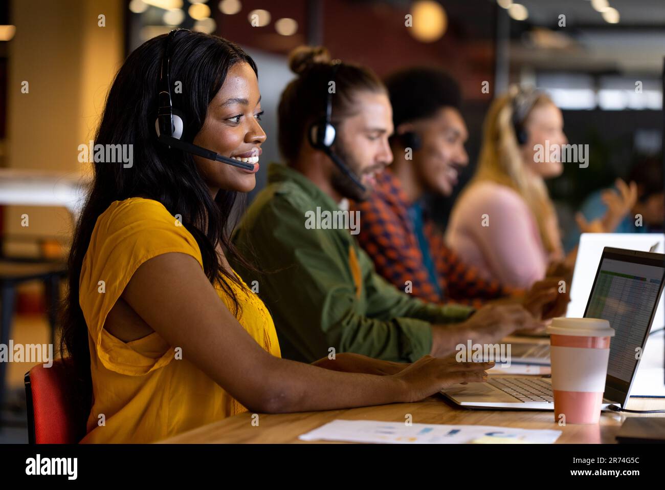 Happy diverse colleagues in phone headsets using computers in office ...