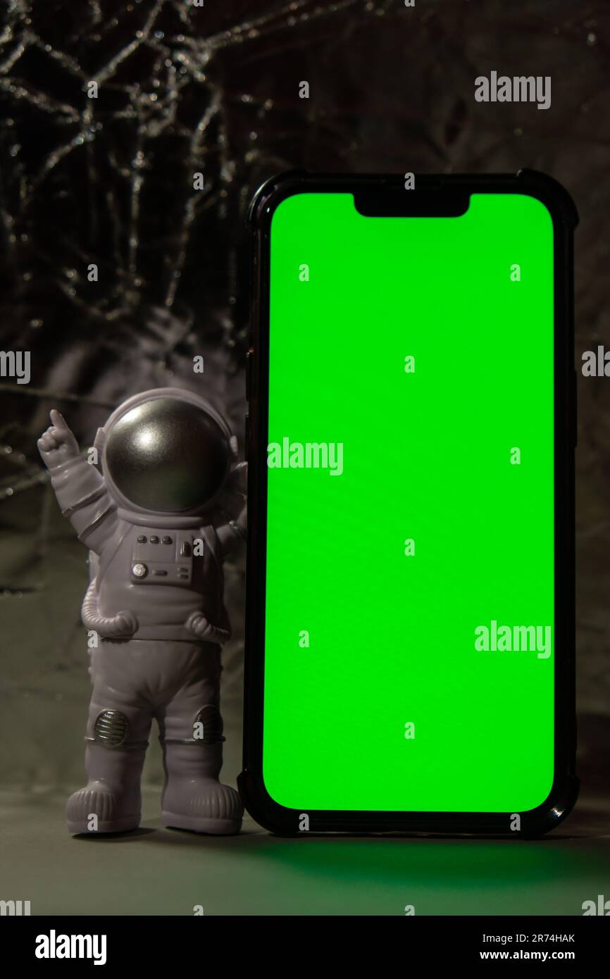 Plastic toy figure astronaut with mobile phone chroma key green screen ...