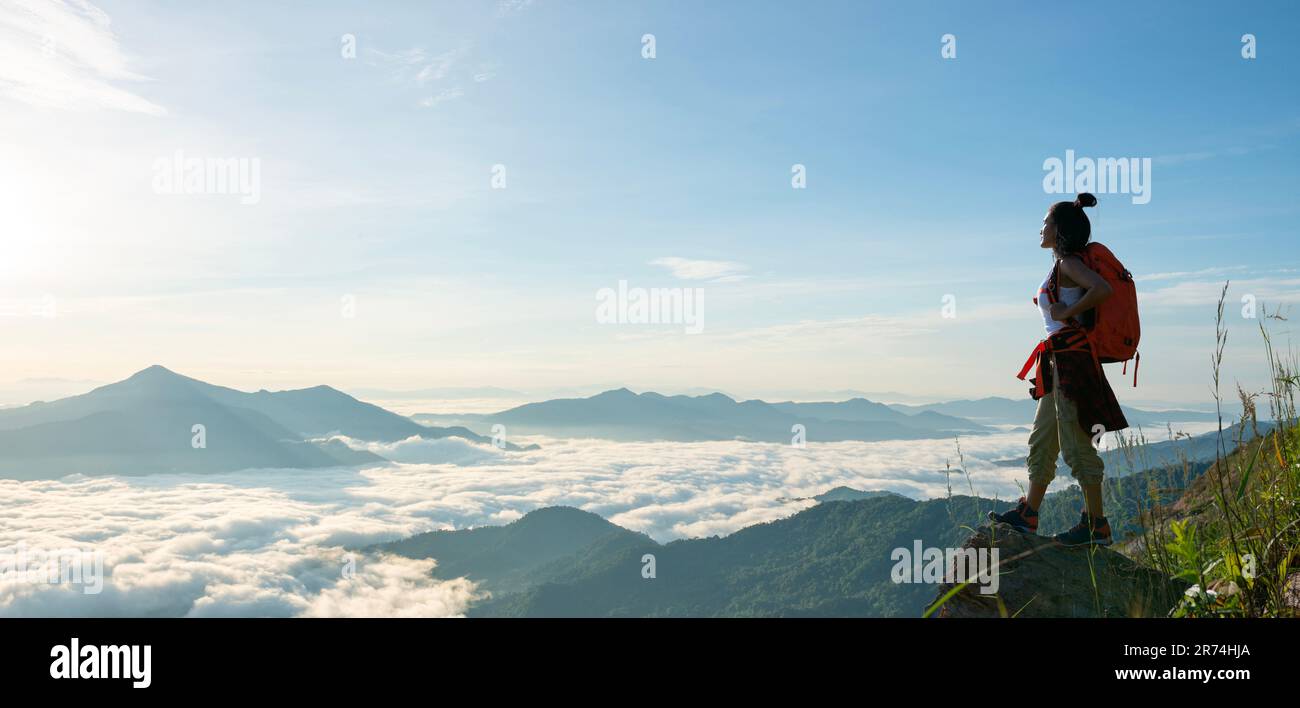 Female hiker standing and watching the sea of mist on the top of a high ...
