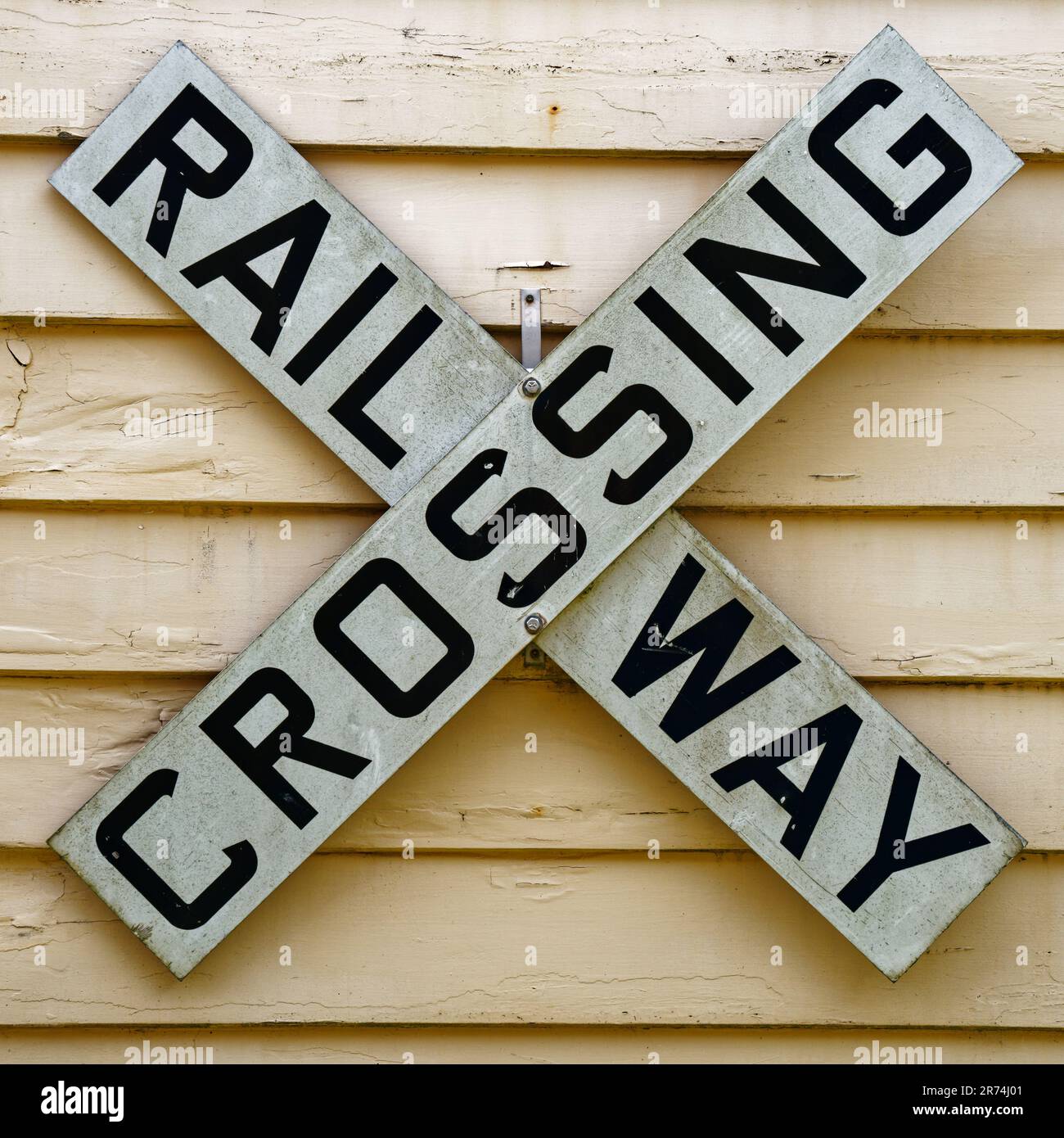 A railway crossing sign on the side of a weatherboard building ...