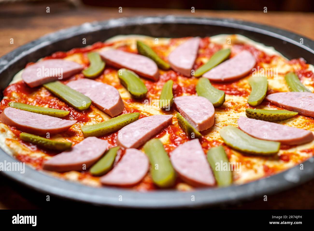 Pickled cucumbers laid out on a pizza crust covered with tomato sauce ...