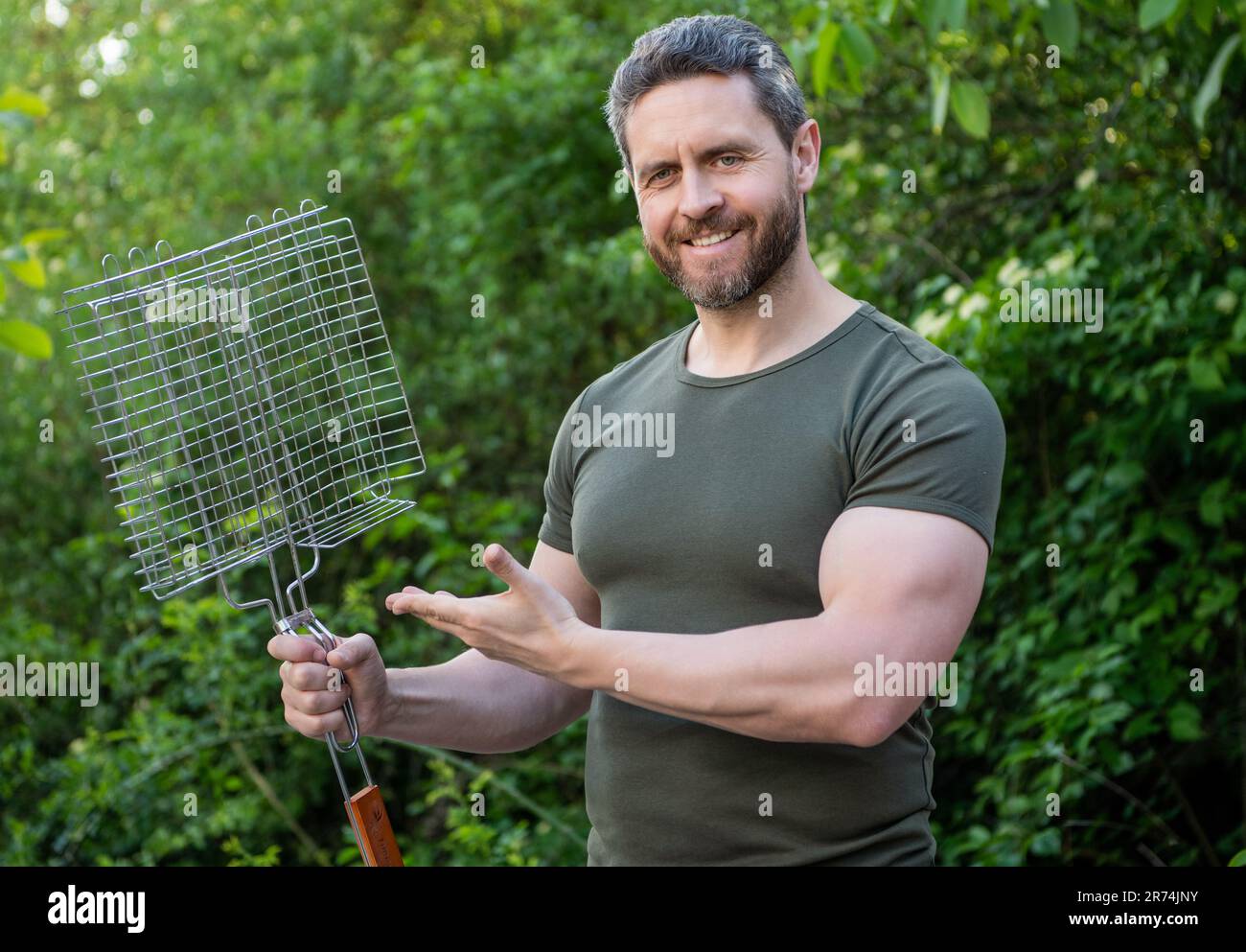 happy man presenting barbecue grill utensil. photo of man with barbecue ...