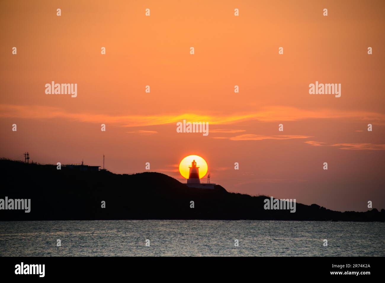 At dusk, the sun is behind the lighthouse. The Fugui Cape Lighthouse in ...
