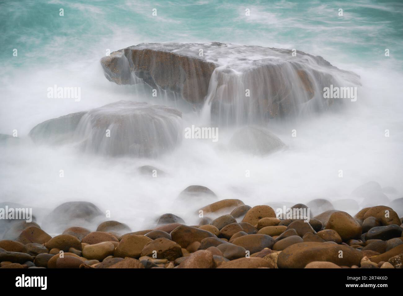 White waves flow slowly from the rocks into the sea. Slow exposure shot ...