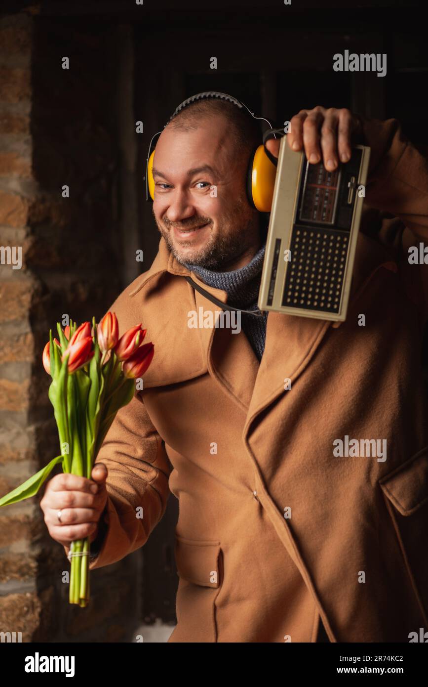 Funny look of a man with a bouquet, a retro radio and headphones in a ...