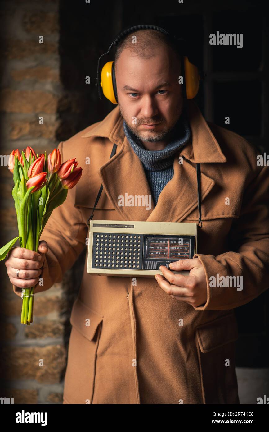 Funny look of a man with a bouquet, a retro radio and headphones in a ...