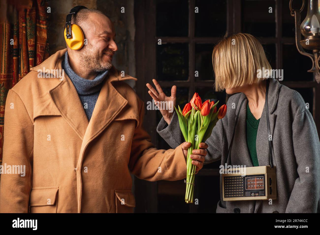 Funny photo of a man in headphones from the noise who gives a bouquet ...