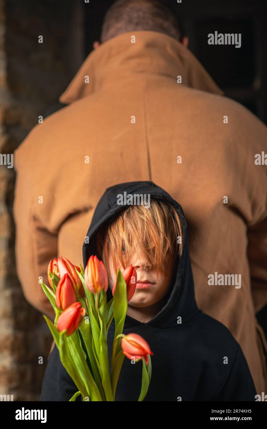 A young boy with a bouquet of flowers and a man turned away. Quarrel ...