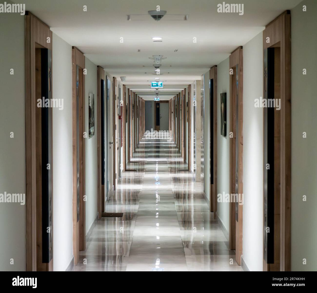 Long corridor in hotel with many doors and light in end from big window ...