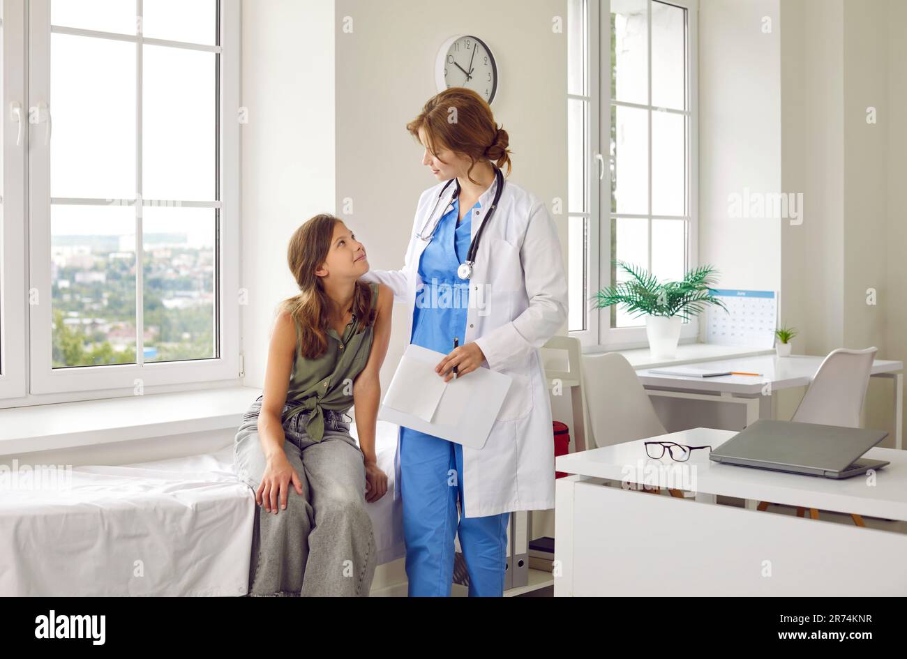 Doctor looking at her young teenager girl patient and giving ...