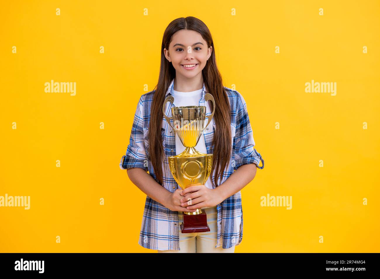 cheerful teen girl hold her award champion cup isolated on yellow. teen ...