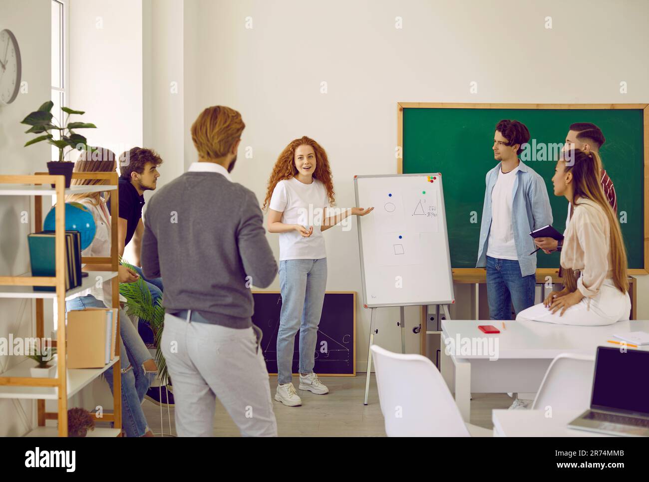Group of students together with teacher listening to young girl giving ...