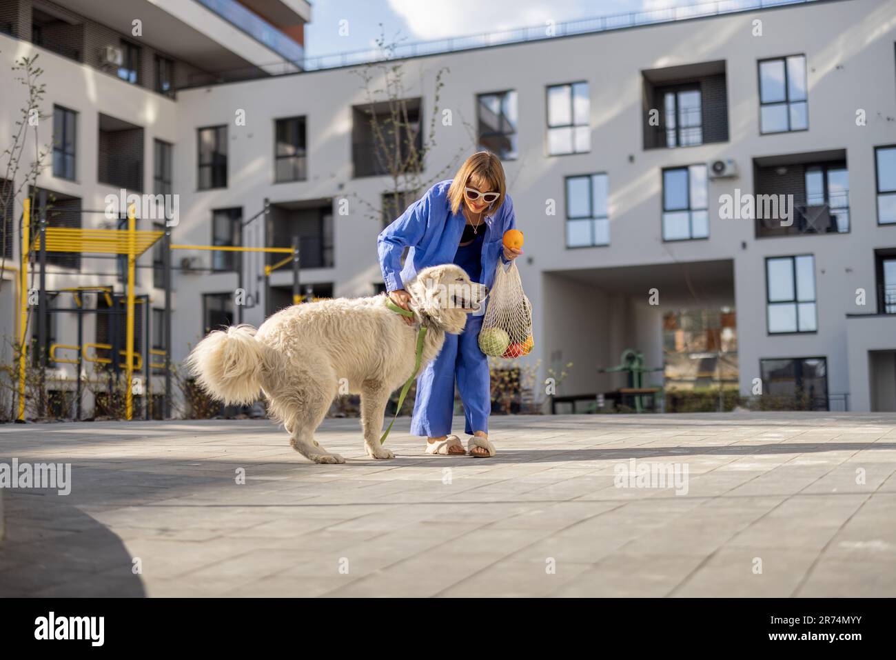 Woman carrying meshbag with fresh groceries while walking home with her ...