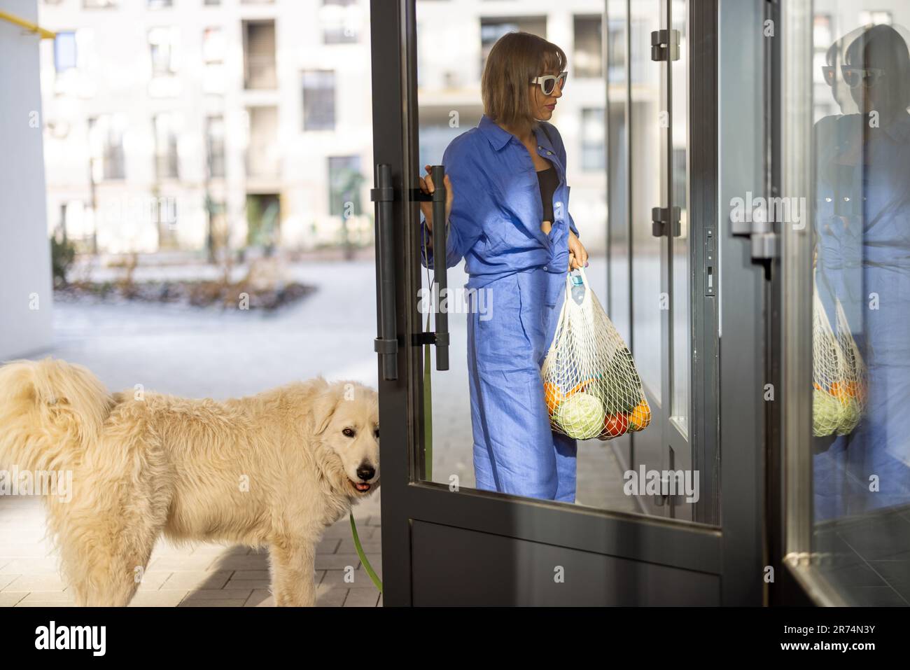 Woman with dog entering apartment building Stock Photo - Alamy