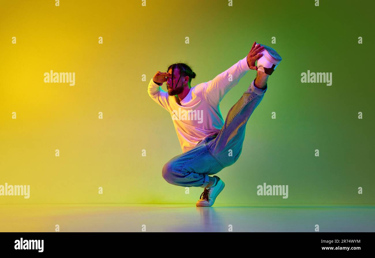 Street dancer. Young man with dreads hairdo, in casual clothes dancing ...