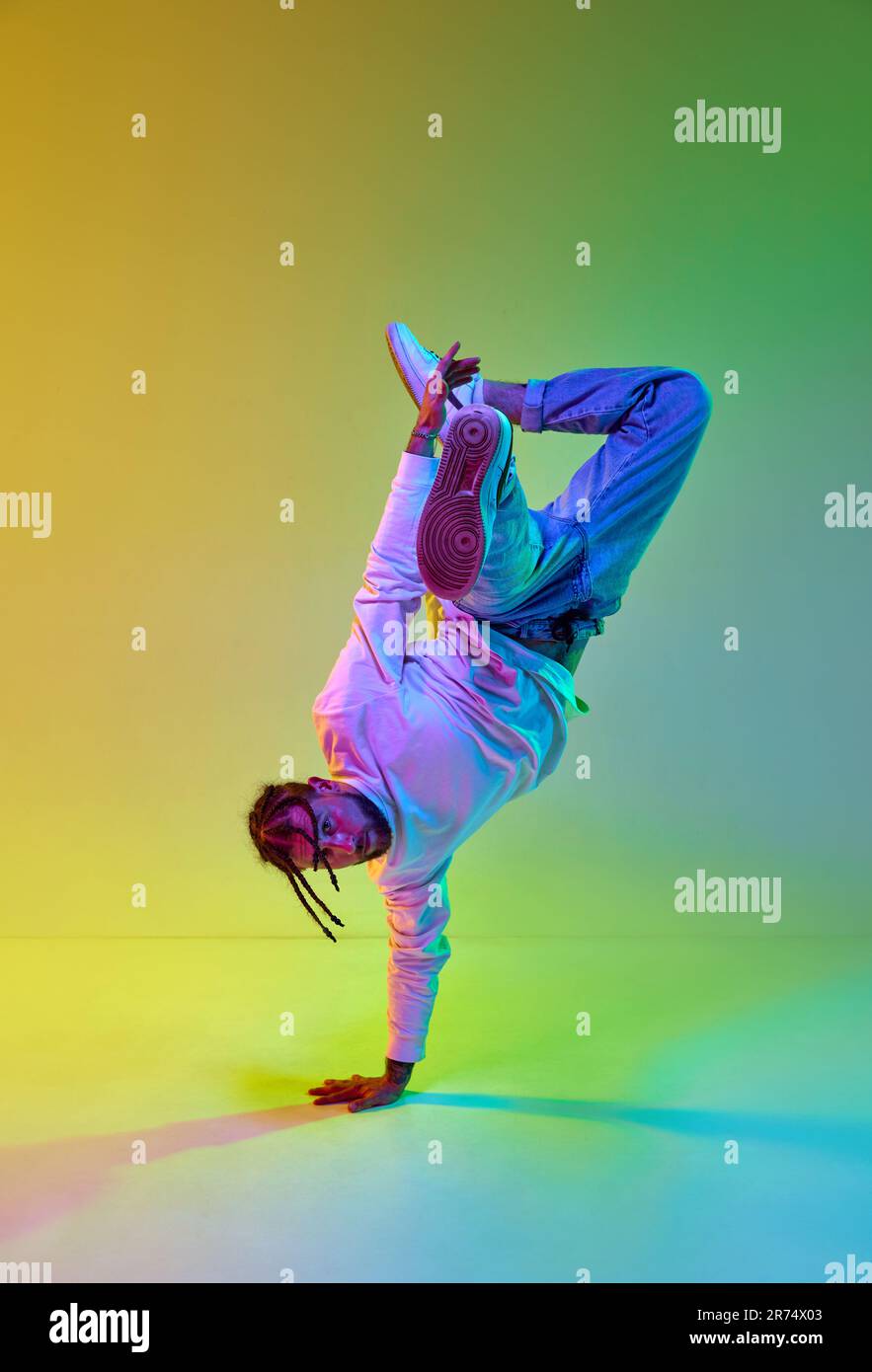 Young sportive guy with dreads hairstyle dancing hip-hop, breakdance ...