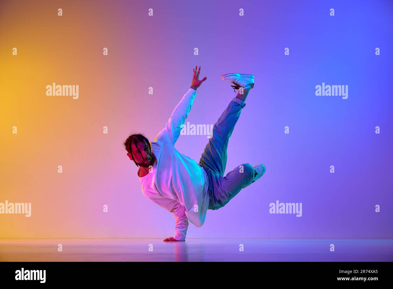 Dance show. Young guy dancing contemp, breakdance and hip-hop against gradient multicolored ...