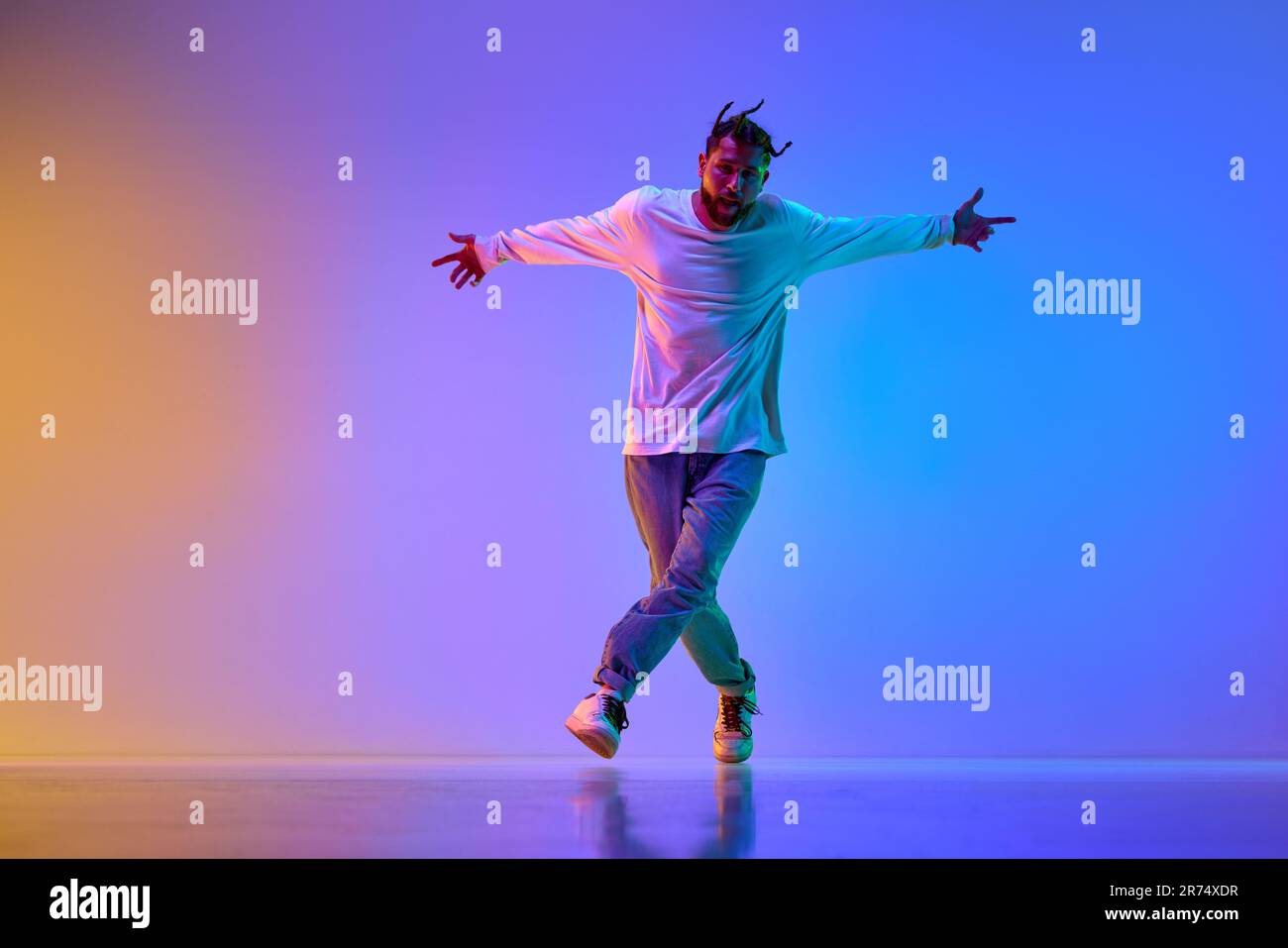 Young handsome guy in casual clothes and dreads dancing breakdance ...