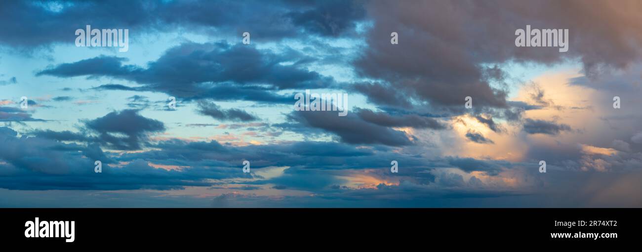 Deep indigo storm clouds hang against the horizon in the rays of the ...