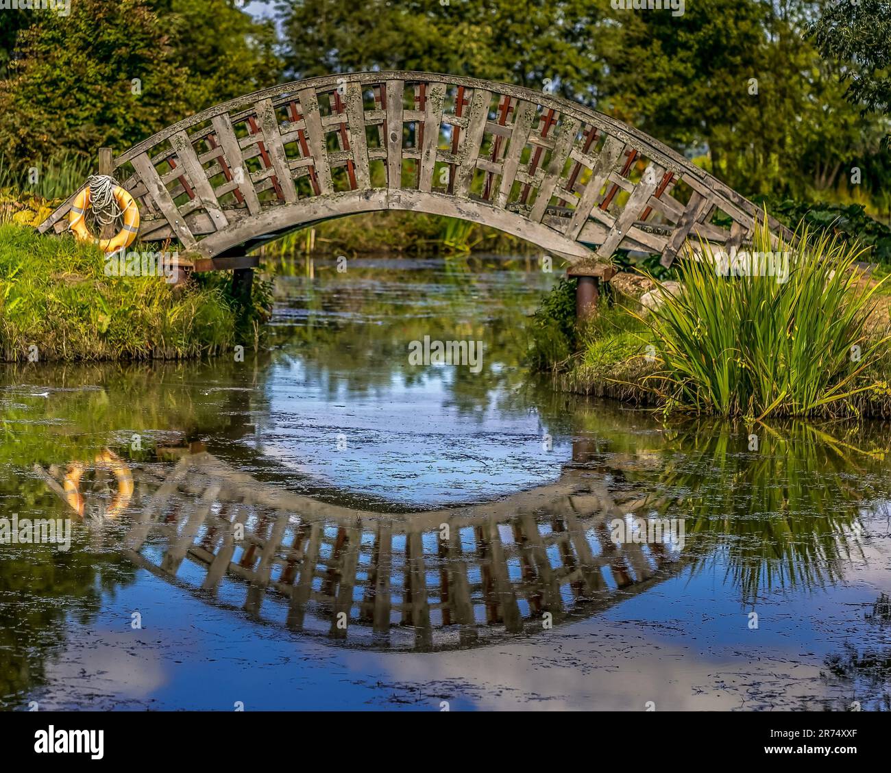 A small arched wooden bridge over a pond at Burgie Arboretum in the ...