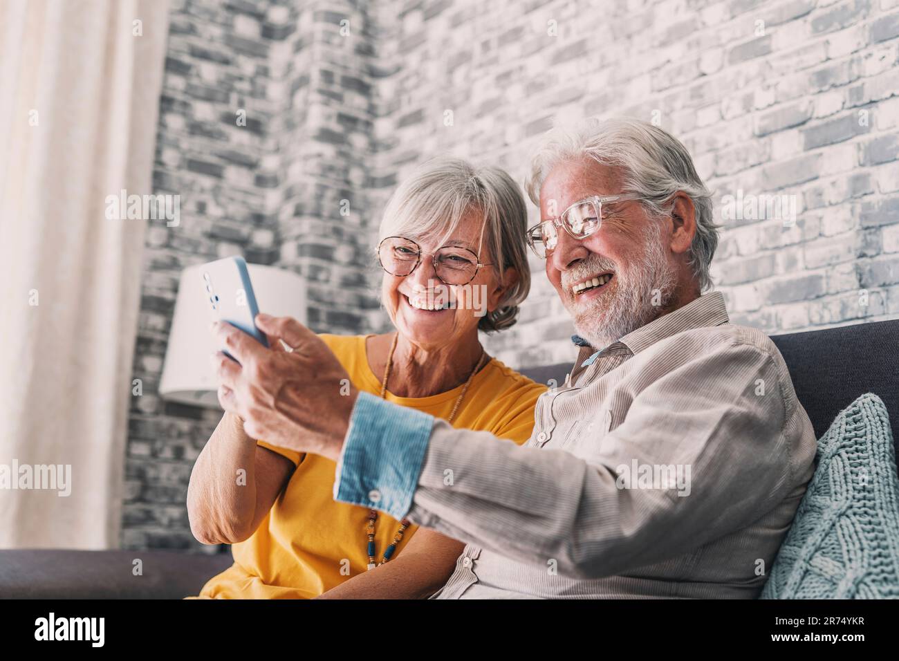 Happy retired family couple using mobile phone for video call together ...