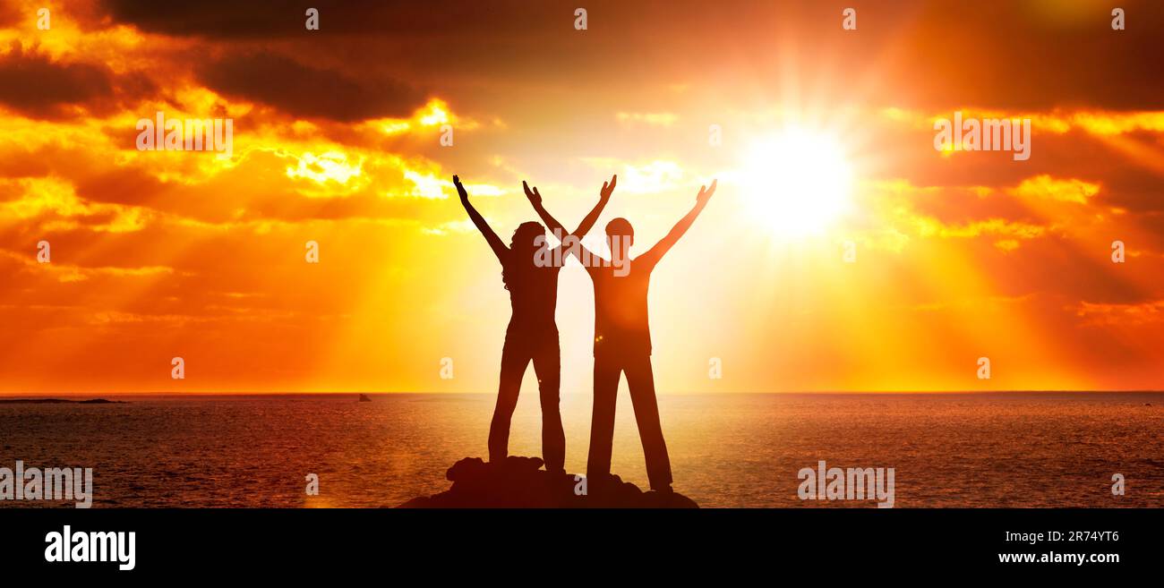 Two people with arms raised against the light at sunset Stock Photo - Alamy