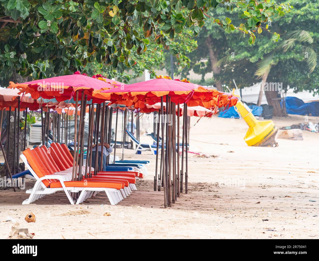 Beach in Pattaya, Thailand with empty beach chairs and a yellow buoy in ...