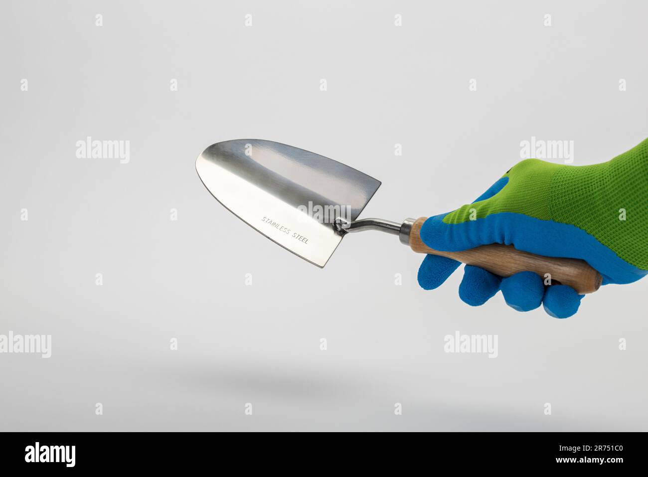 Hand with work glove holding flower trowel, white background Stock ...