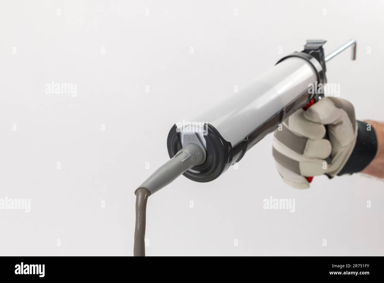 Man hand with glove holds cartridge press, silicone sealant is pressed ...