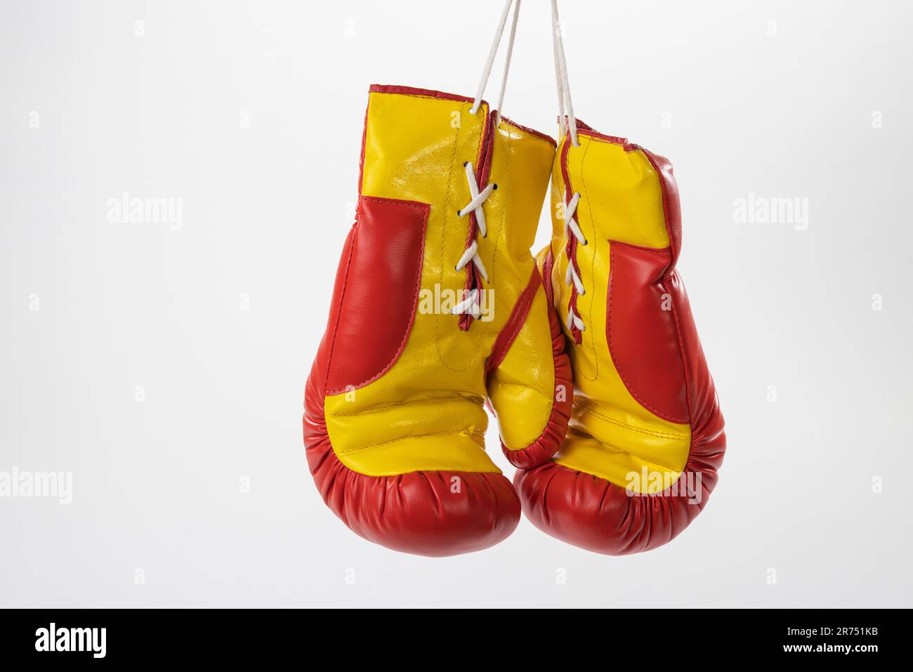 Pair of red and yellow boxing gloves hung on lace, white background ...