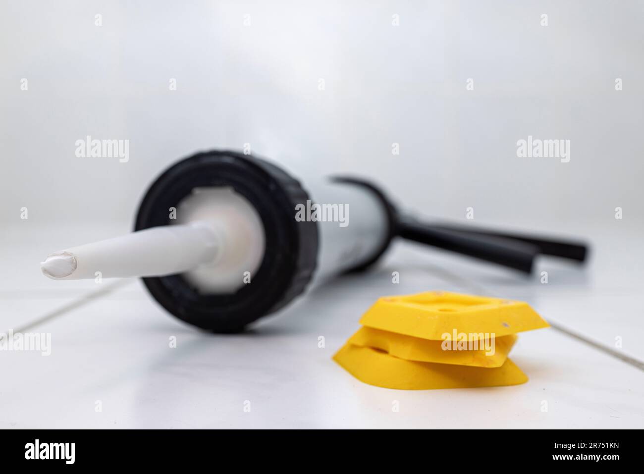 Cartridge press lies on floor tile, cartridge nozzle, silicone grout ...