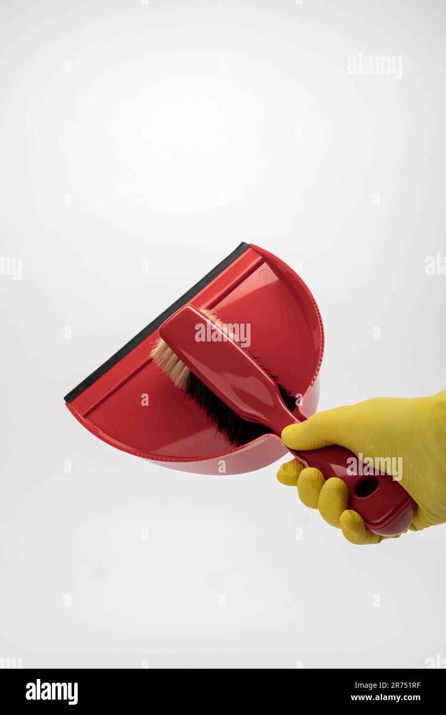 Hand holding red sweeping set, protective glove yellow, white ...