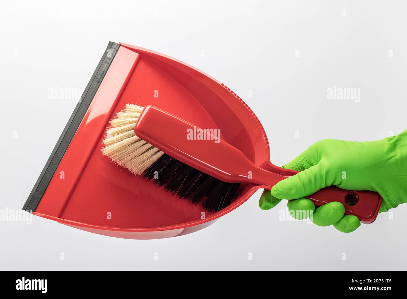 Hand holding red sweeping set, protective glove green, white background ...