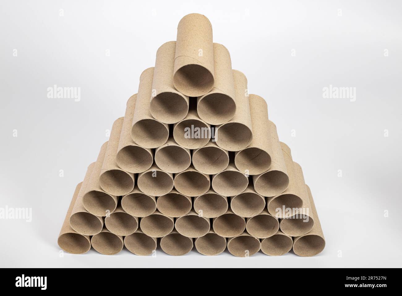 Many empty toilet paper rolls stacked as a pyramid, white background ...