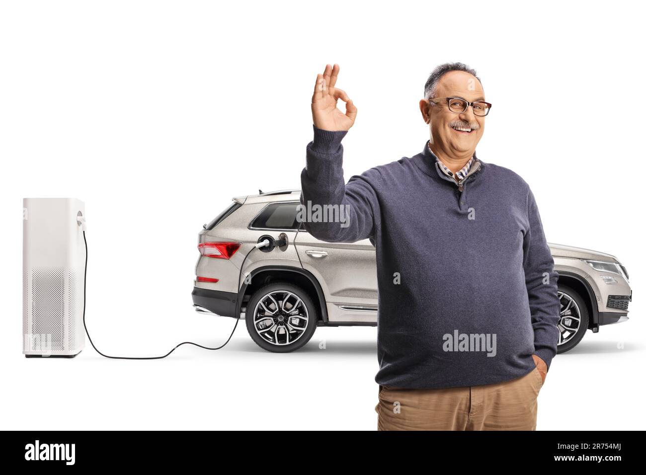Cheerful mature man gesturing ok sign and charging electrical vehicle ...