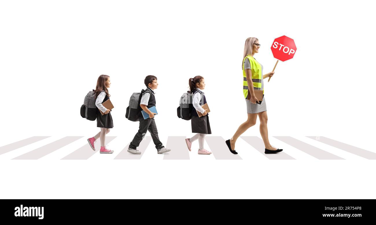 Teacher and schoolchildren in safety vests crossing a street and ...