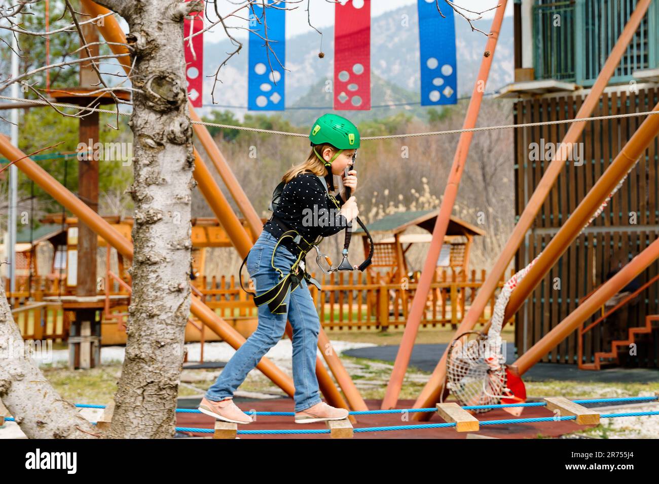 Teenage teen girl in climbing harness equipment, green sports safety ...