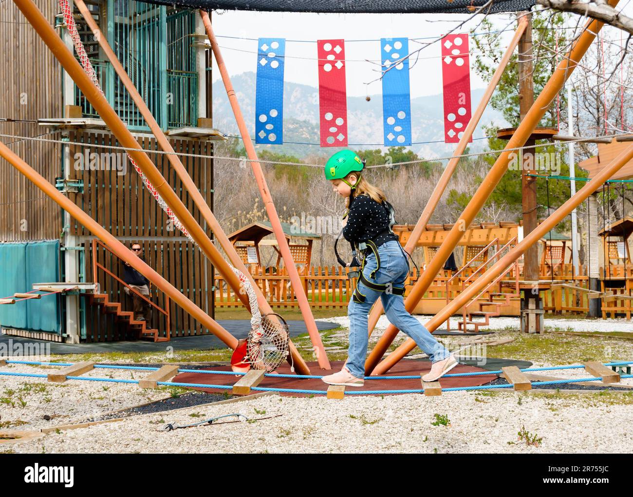 Teenage teen girl in climbing harness equipment, green sports safety ...