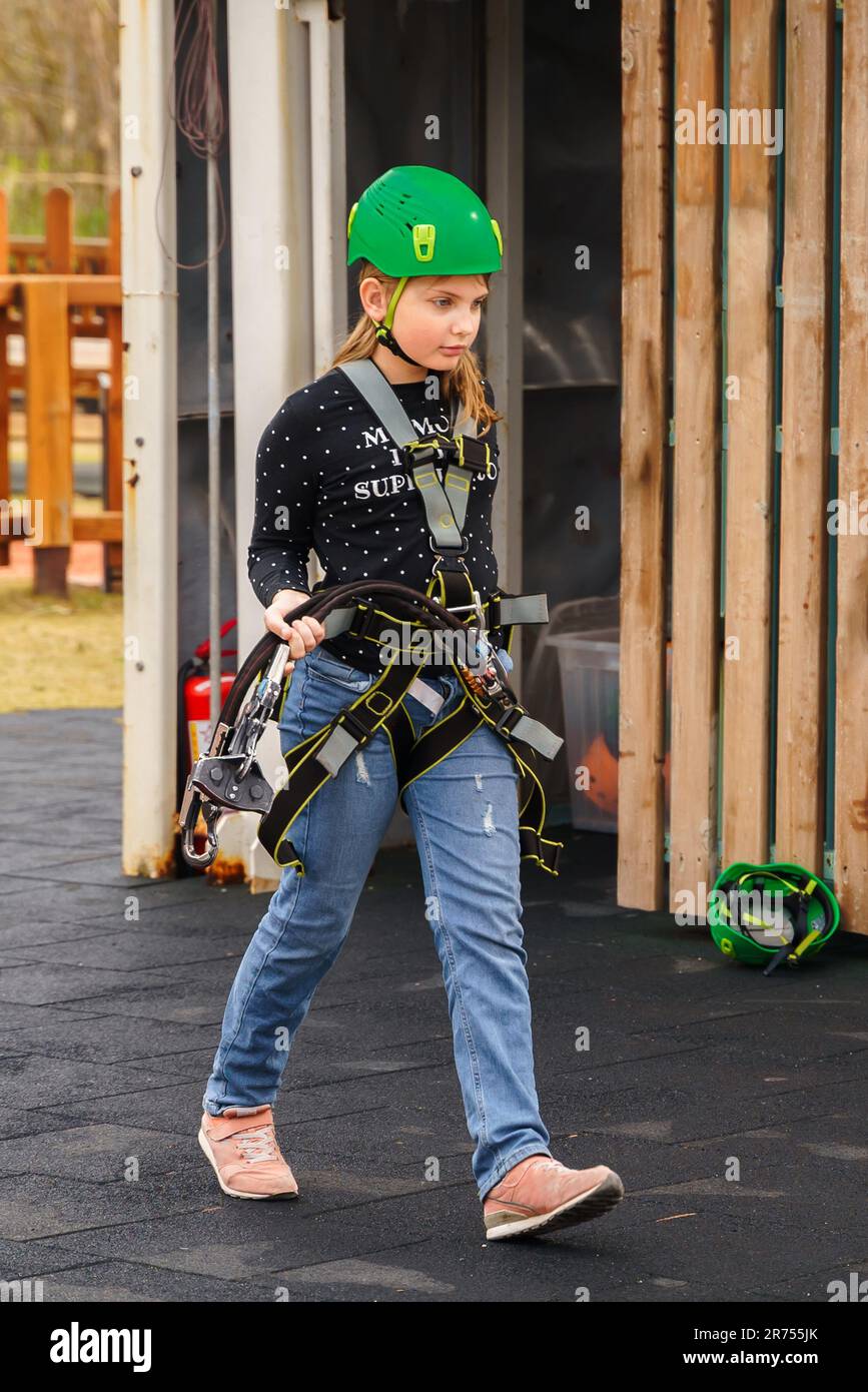 Teenage teen girl in climbing harness equipment, green sports safety ...