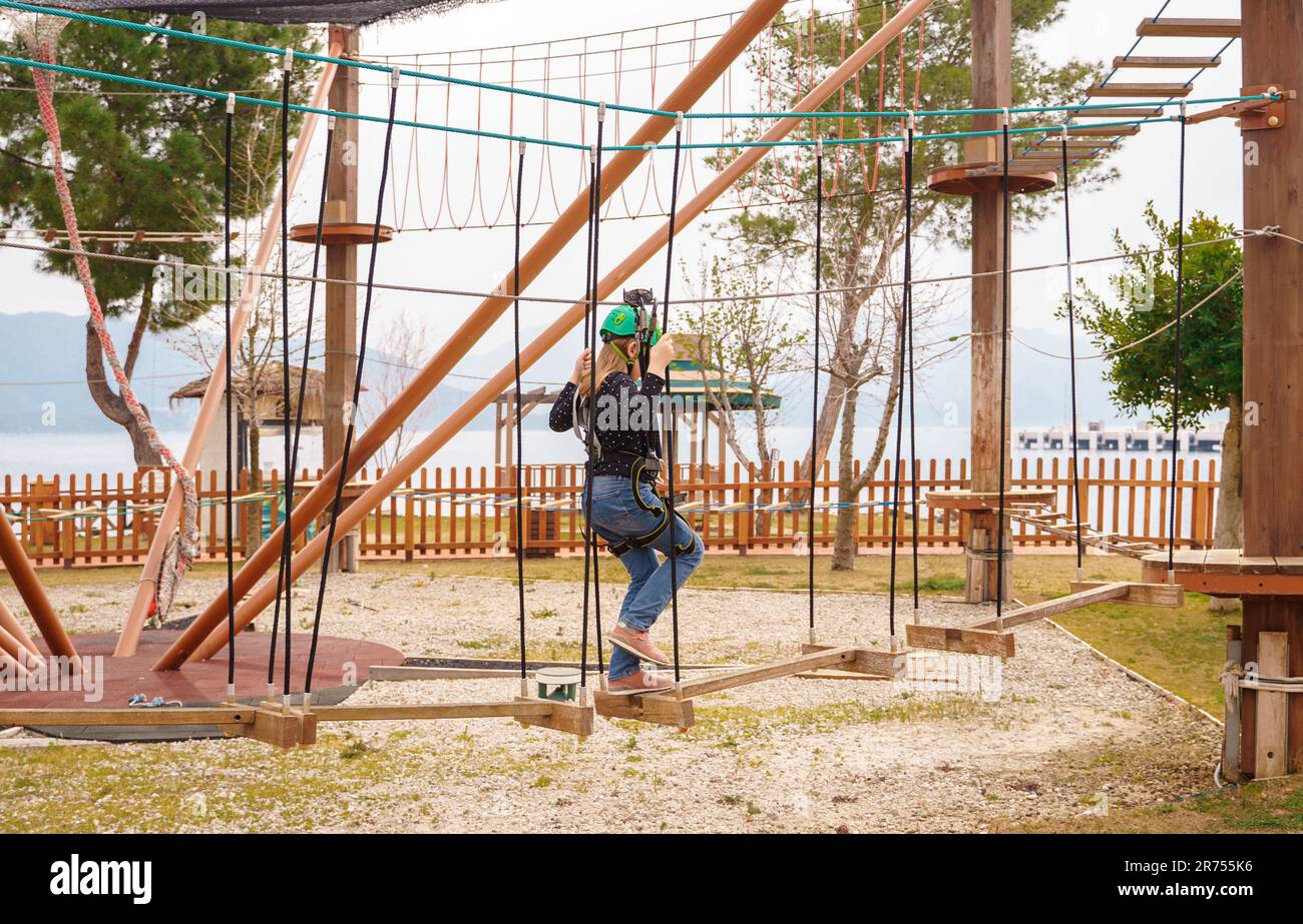 Teenage teen girl in climbing harness equipment, green sports safety ...
